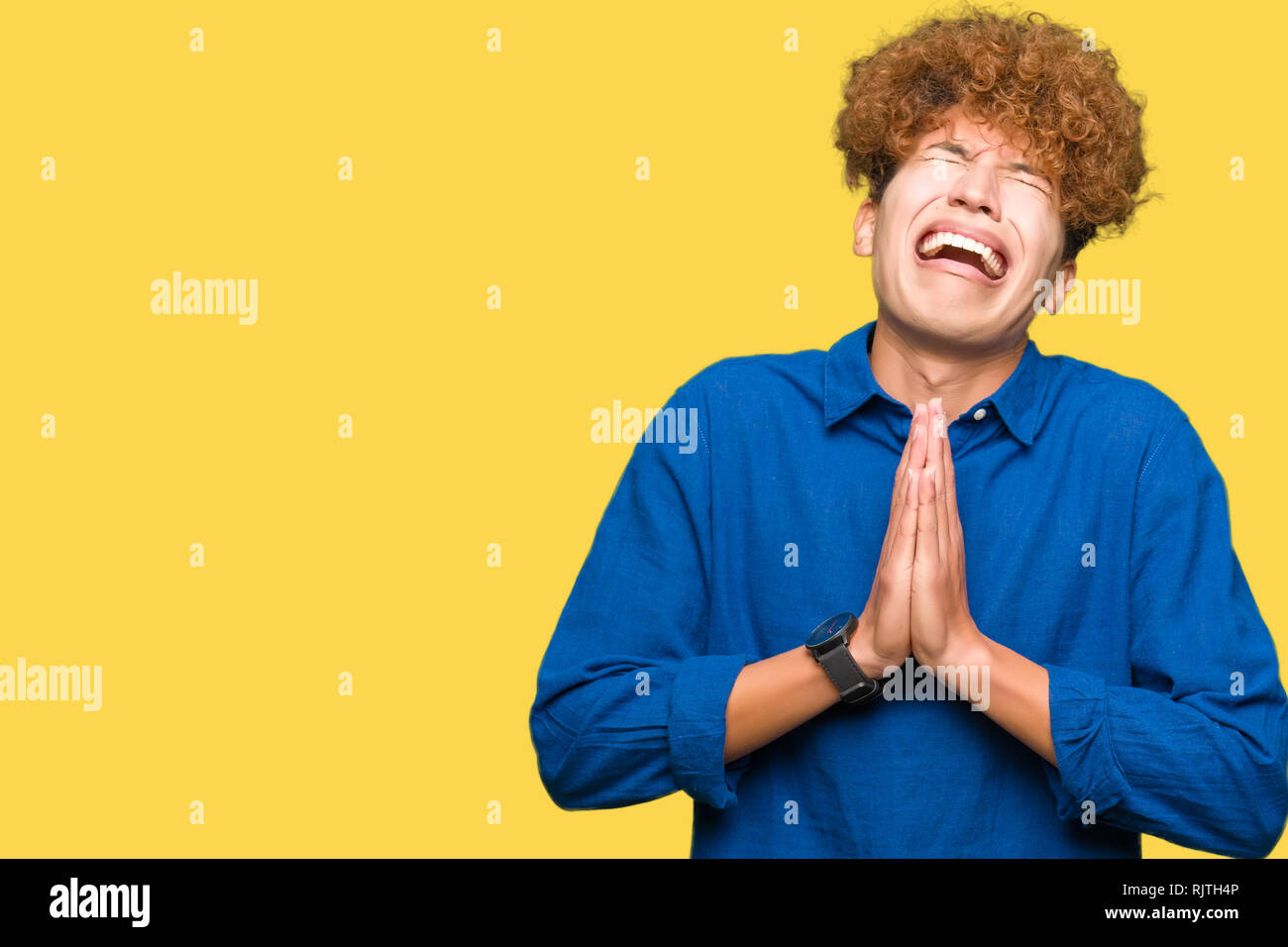Young handsome elegant man with afro hair begging and praying with ...