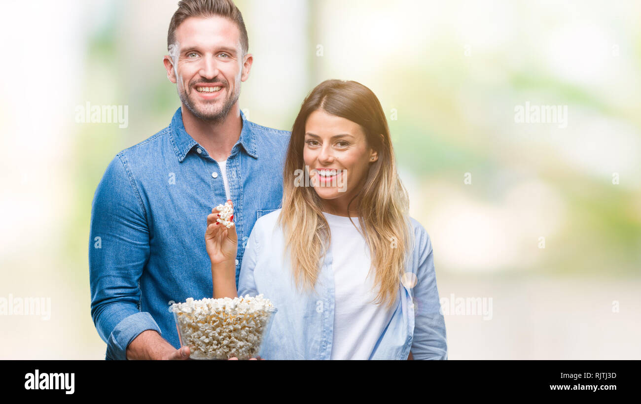 Young couple in love eating popcorn over isolated background with a ...