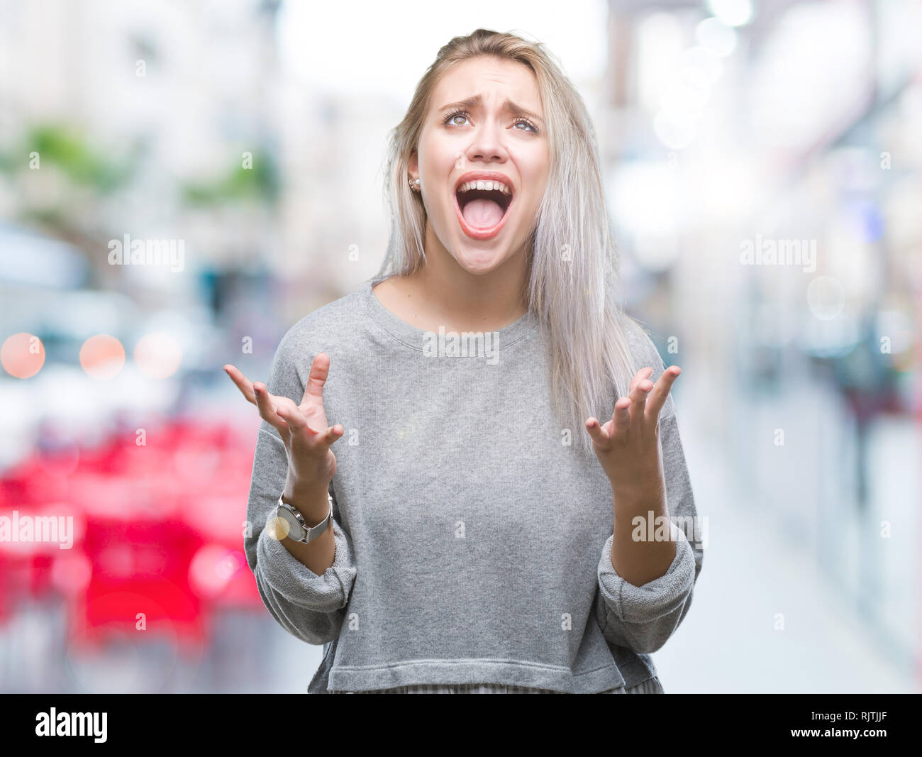 Young blonde woman over isolated background crazy and mad shouting and ...