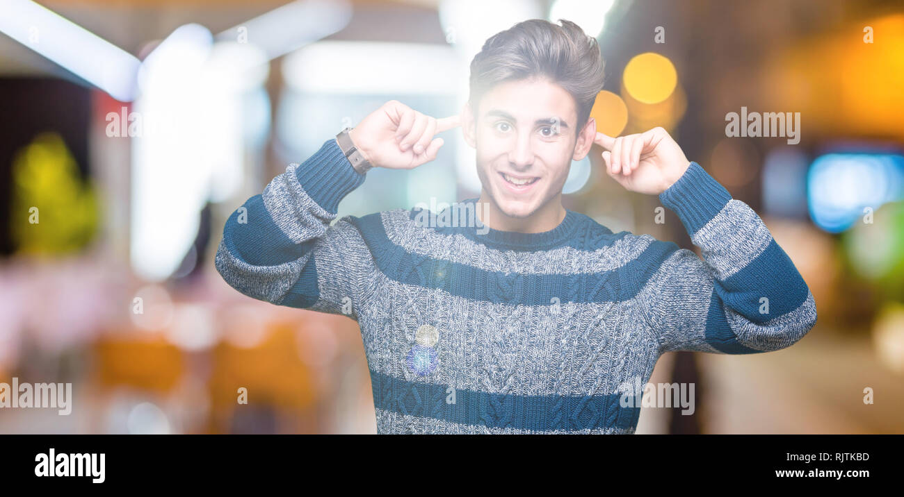 Young handsome man over isolated background Smiling pulling ears with ...