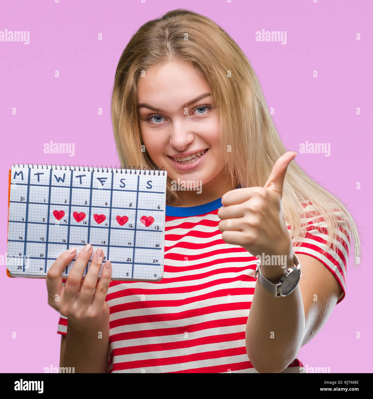 Young caucasian woman holding menstruation calendar over isolated ...
