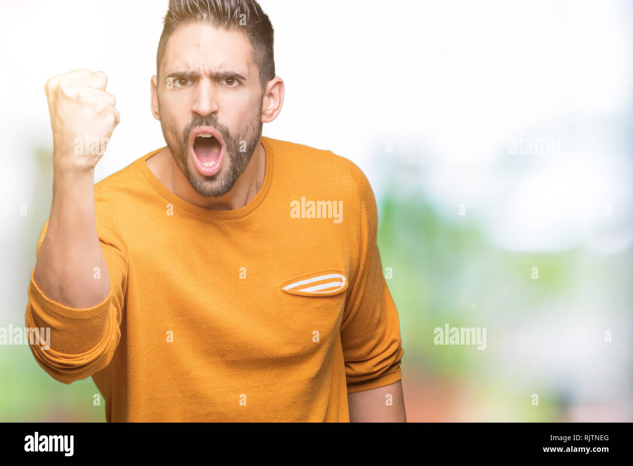 Young handsome man over isolated background angry and mad raising fist ...