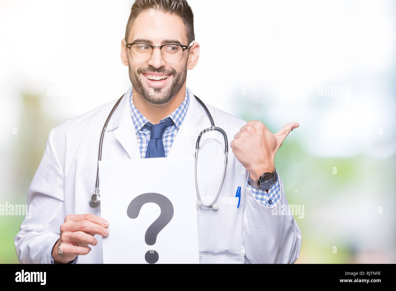 Handsome young doctor man holding paper with question mark over ...