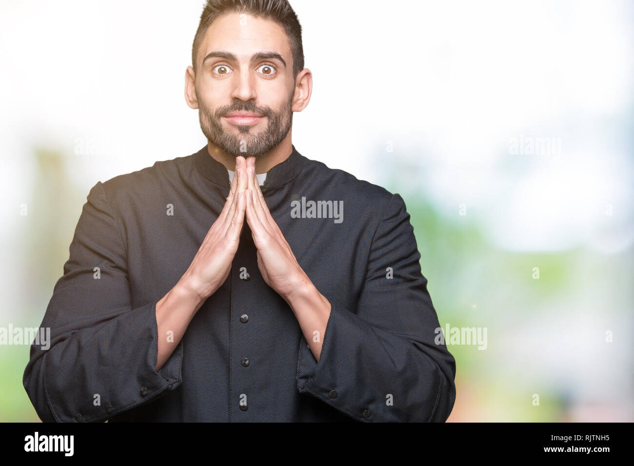 Young Christian priest over isolated background praying with hands ...