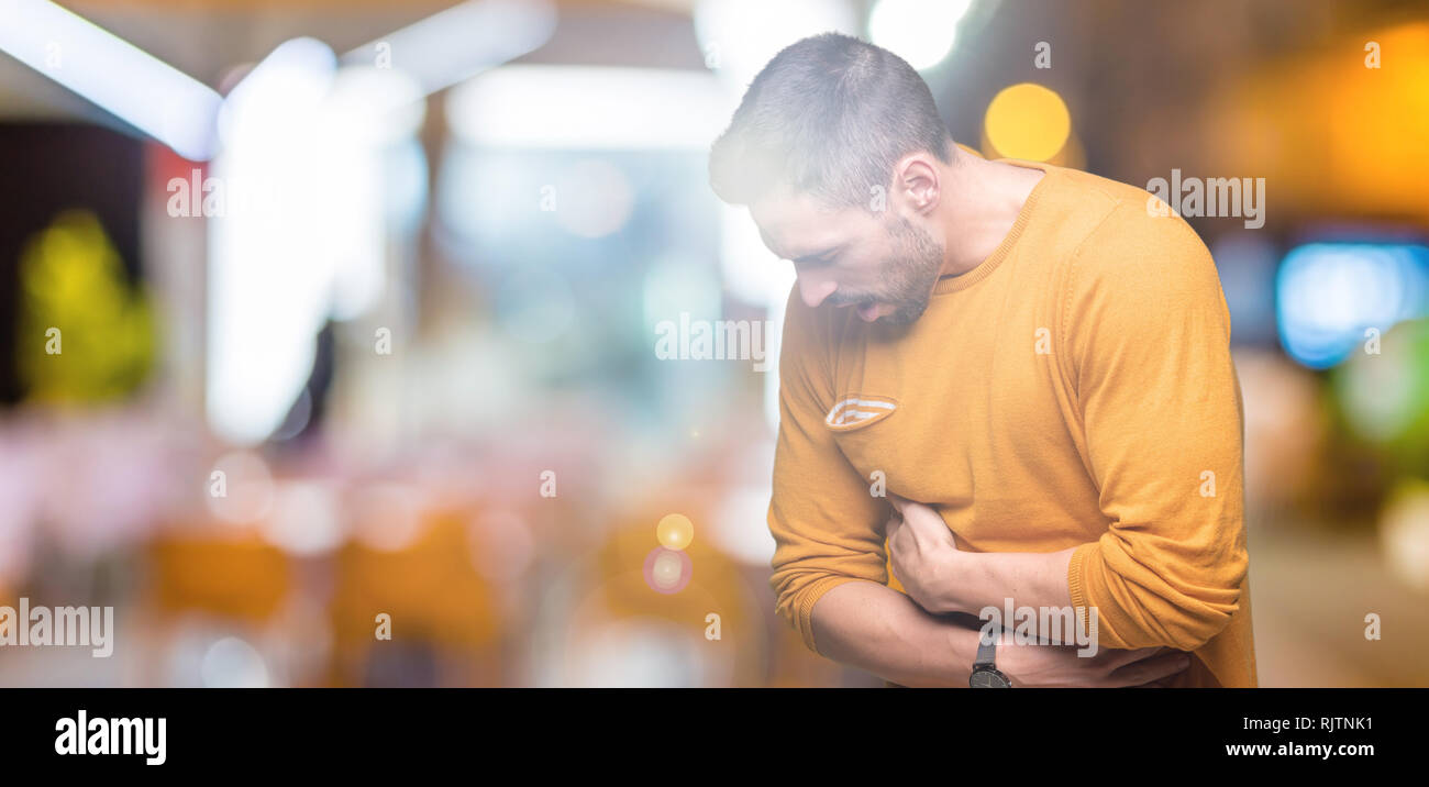 Young handsome man over isolated background with hand on stomach ...