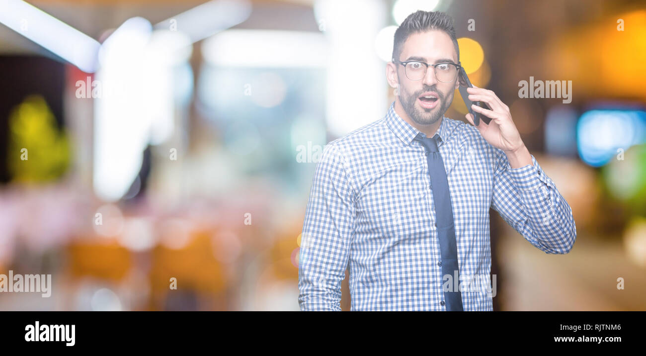 Young business man talking on the phone over isolated background scared ...