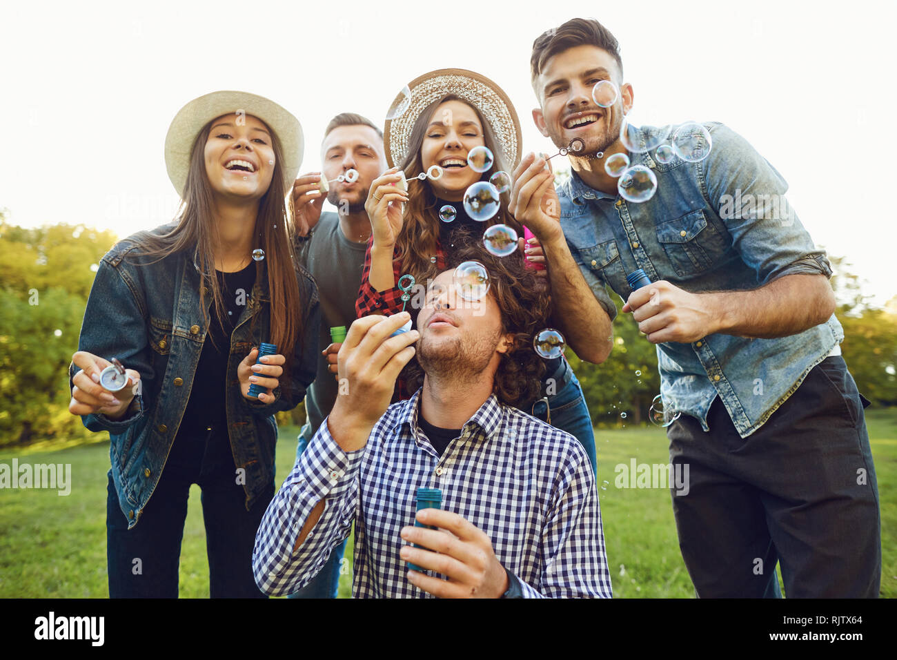 Funny friends with soap bubbles in the park Stock Photo - Alamy