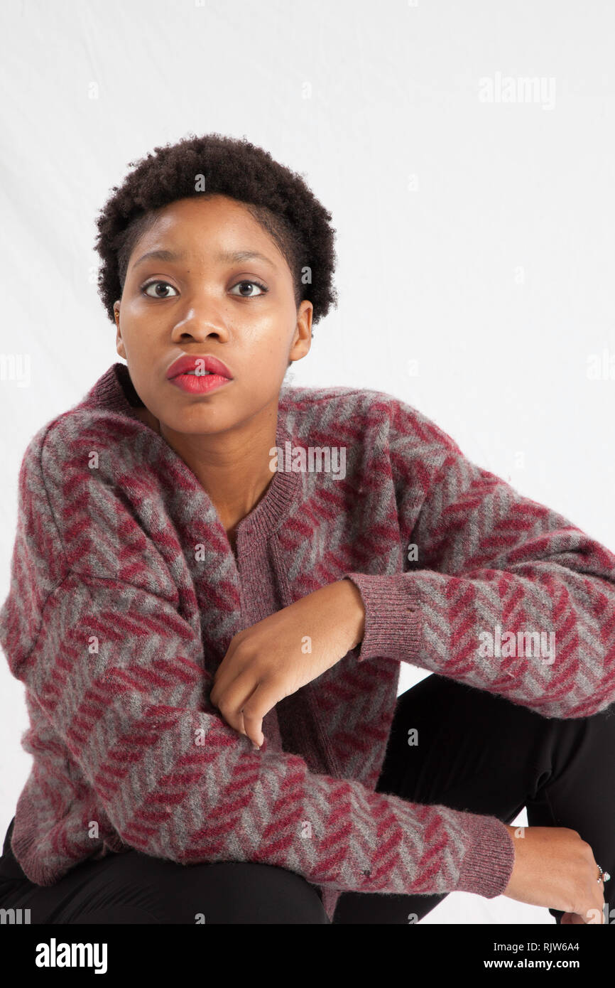 Pensive Black woman in jacket, squatting Stock Photo - Alamy