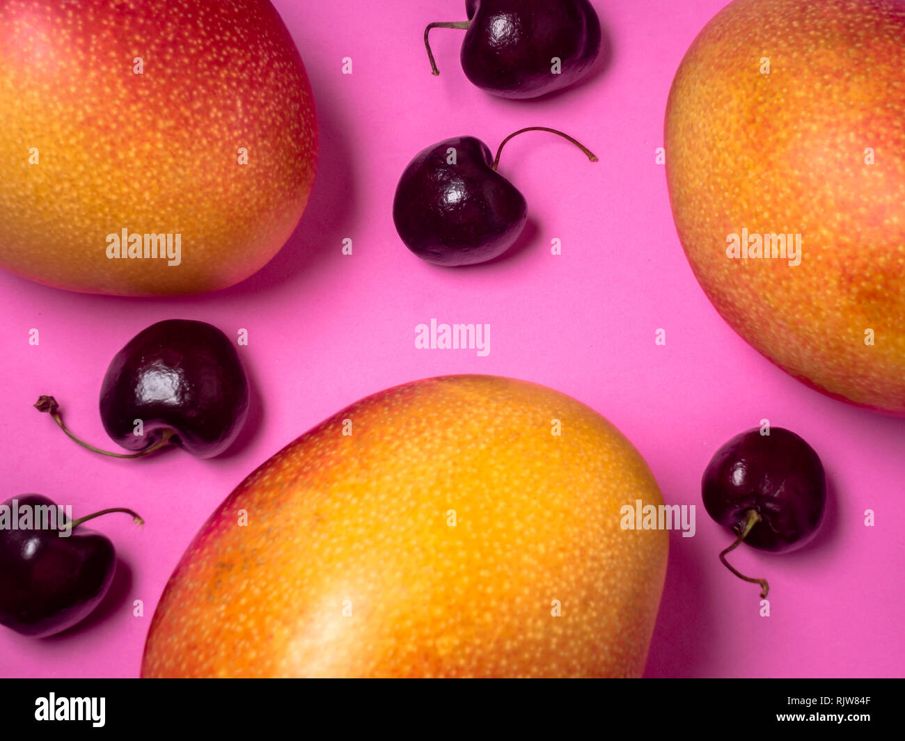 Three Mangos Five Black Cherries on Bright Pink Background Stock Photo ...