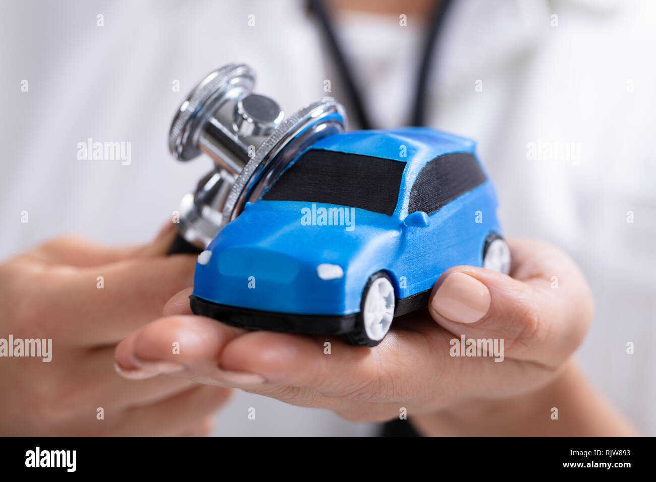 Female Doctor's Hand Examining Miniature Blue Car With Stethoscope ...