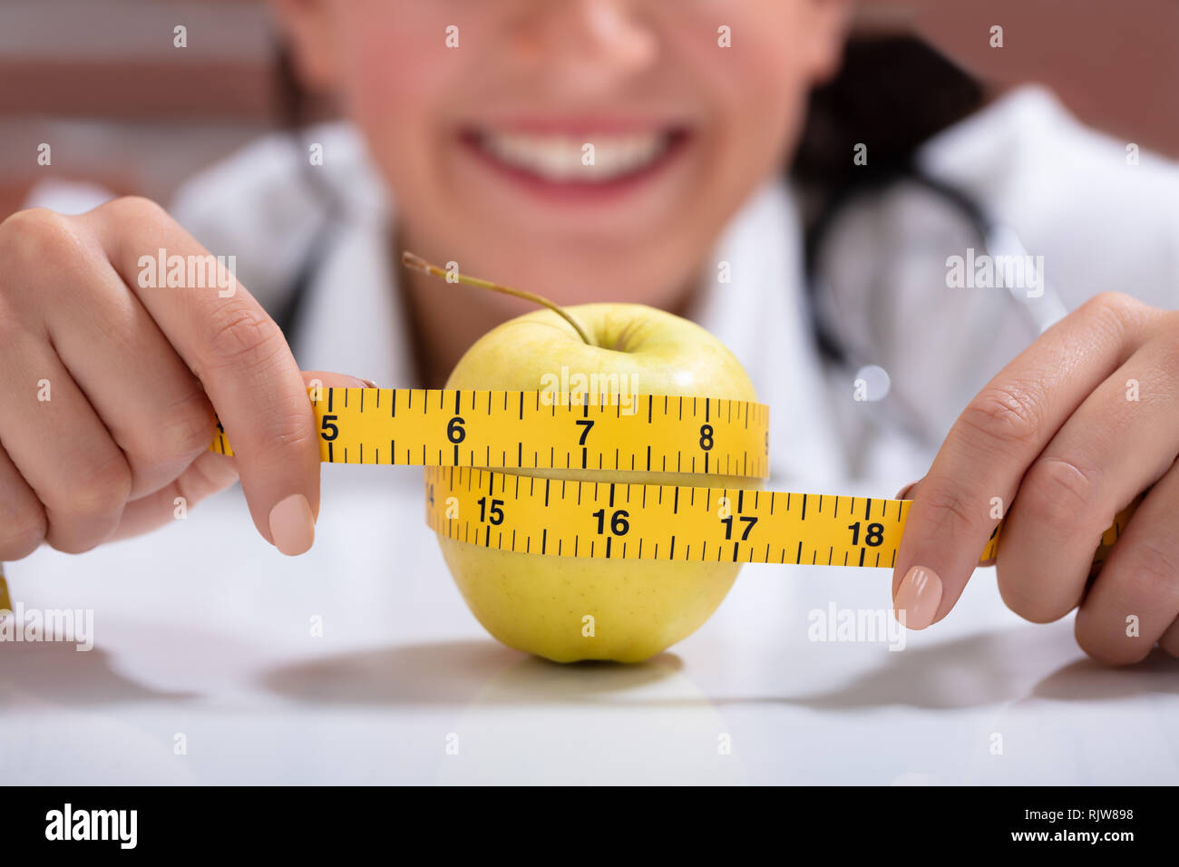 Close-up Of Female Dietitian Measuring The Whole Apple With Measuring ...