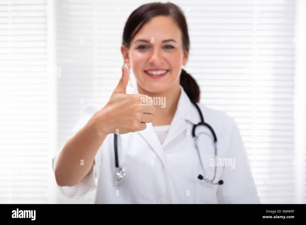 Front View Of Happy Female Doctor Showing Thumb Up Standing In Clinic ...
