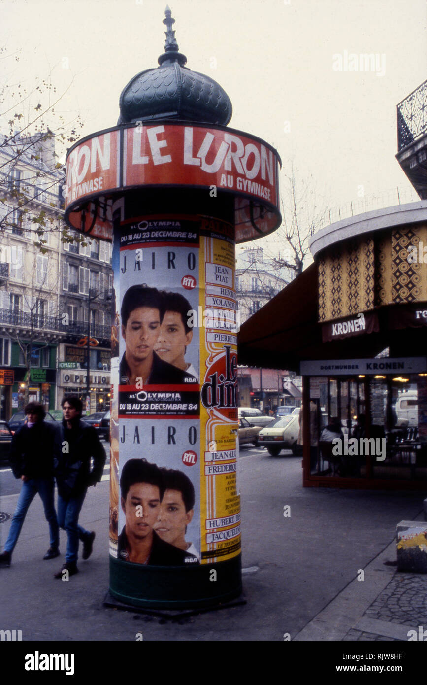 Paris street scene with two young men passing advertising kiosk on the ...