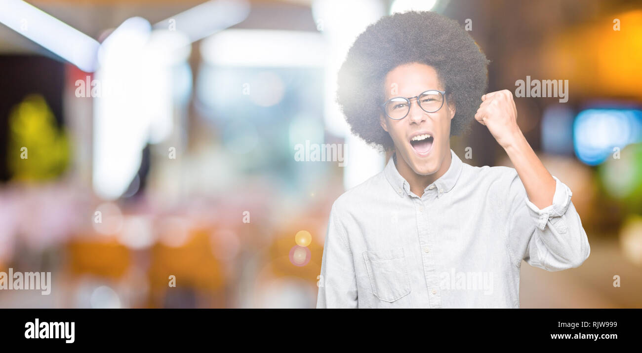 Young african american man with afro hair wearing glasses angry and mad ...