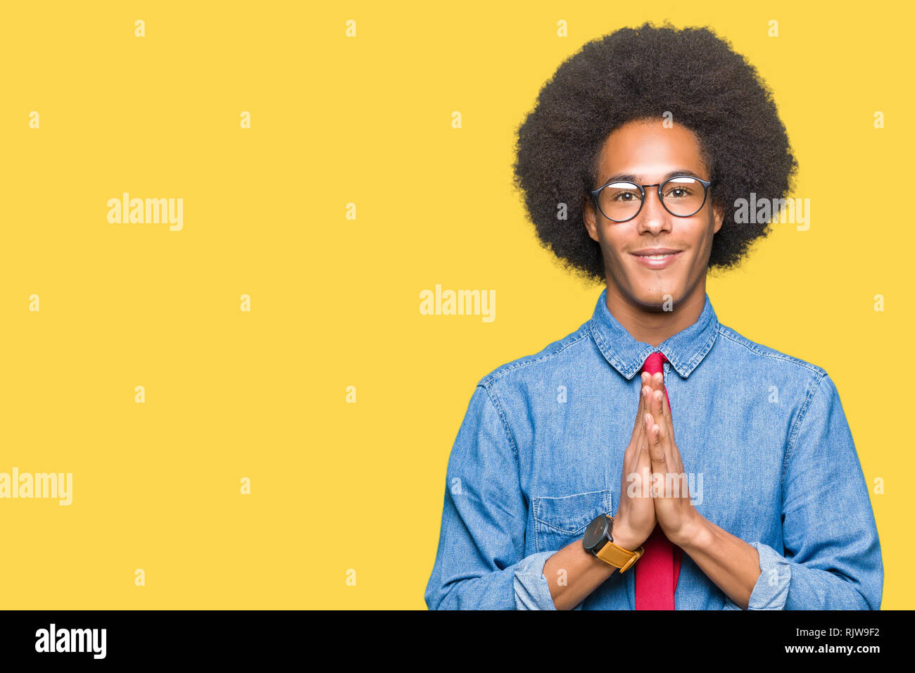 Young african american business man with afro hair wearing glasses and red tie praying with ...