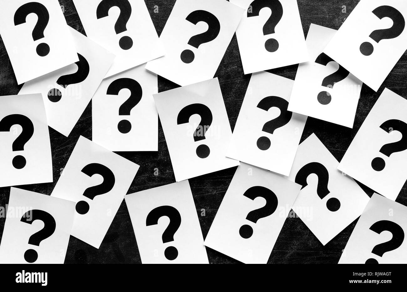 Bold black question marks on paper cards scattered randomly over a ...