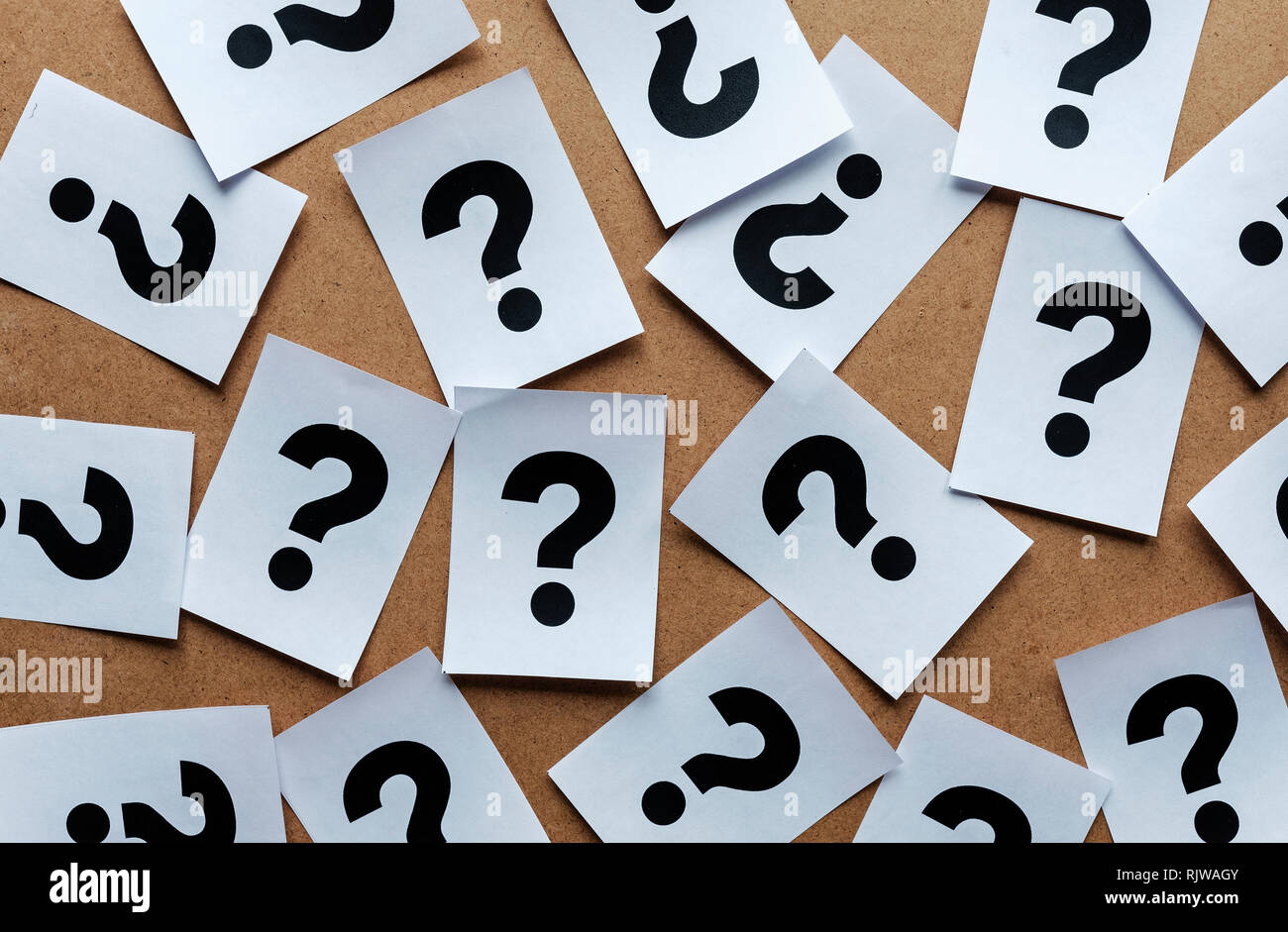 question marks on paper cards scattered randomly over a wooden ...