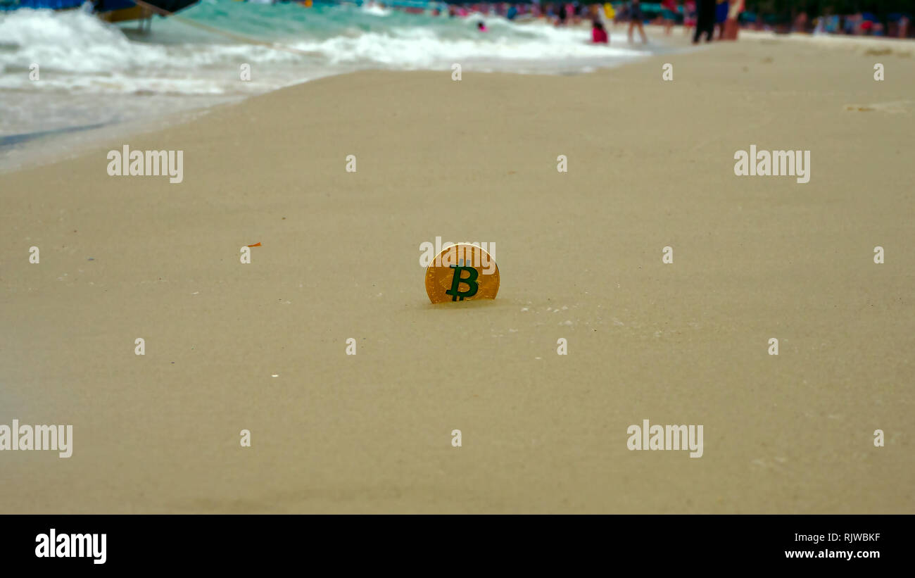 golden bitcoin crypto currency drop on the beach sand by the sea at the ...