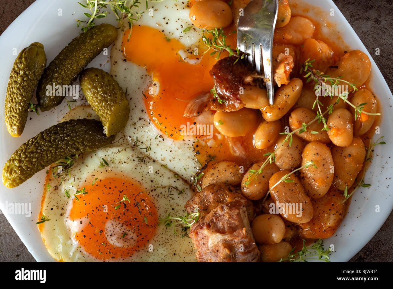 Eating beans with smoked pork meat, eggs and pickles - top view Stock ...