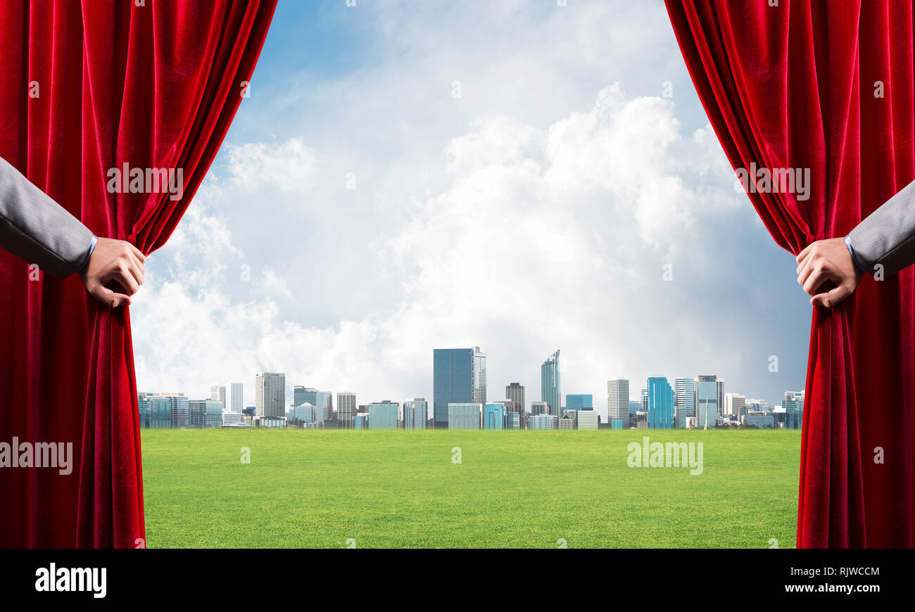 Green meadow behind red curtain and hand holding it Stock Photo - Alamy