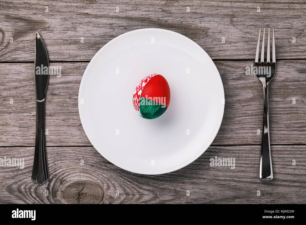 Easter egg, painted in the color of the Belarusian flag on a plate with ...
