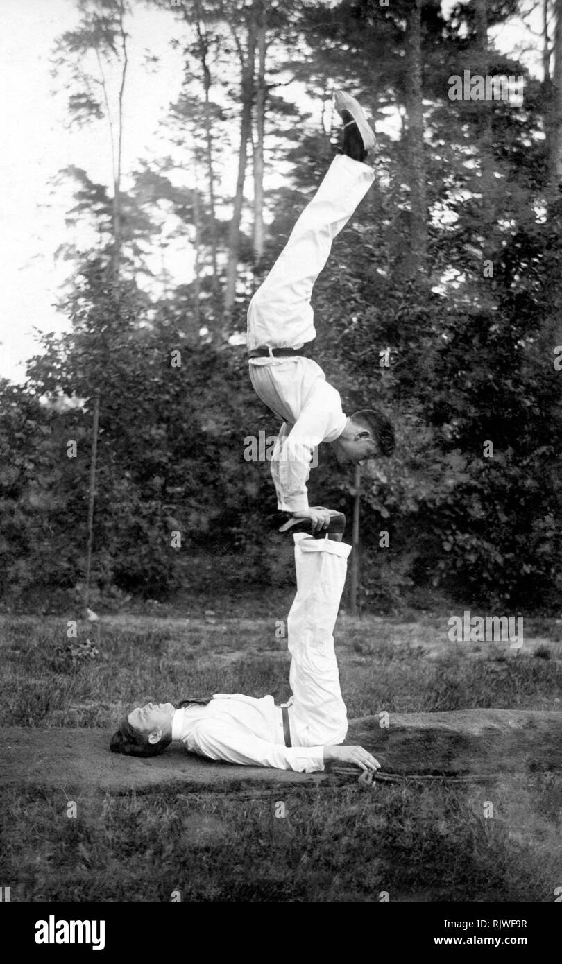Two acrobats training on the meadow, handstand on the feet of their ...