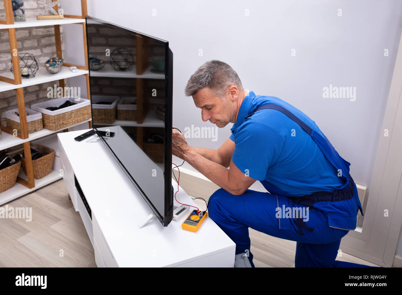 Male Technician Repairing Television With Digital Multimeter At Home ...