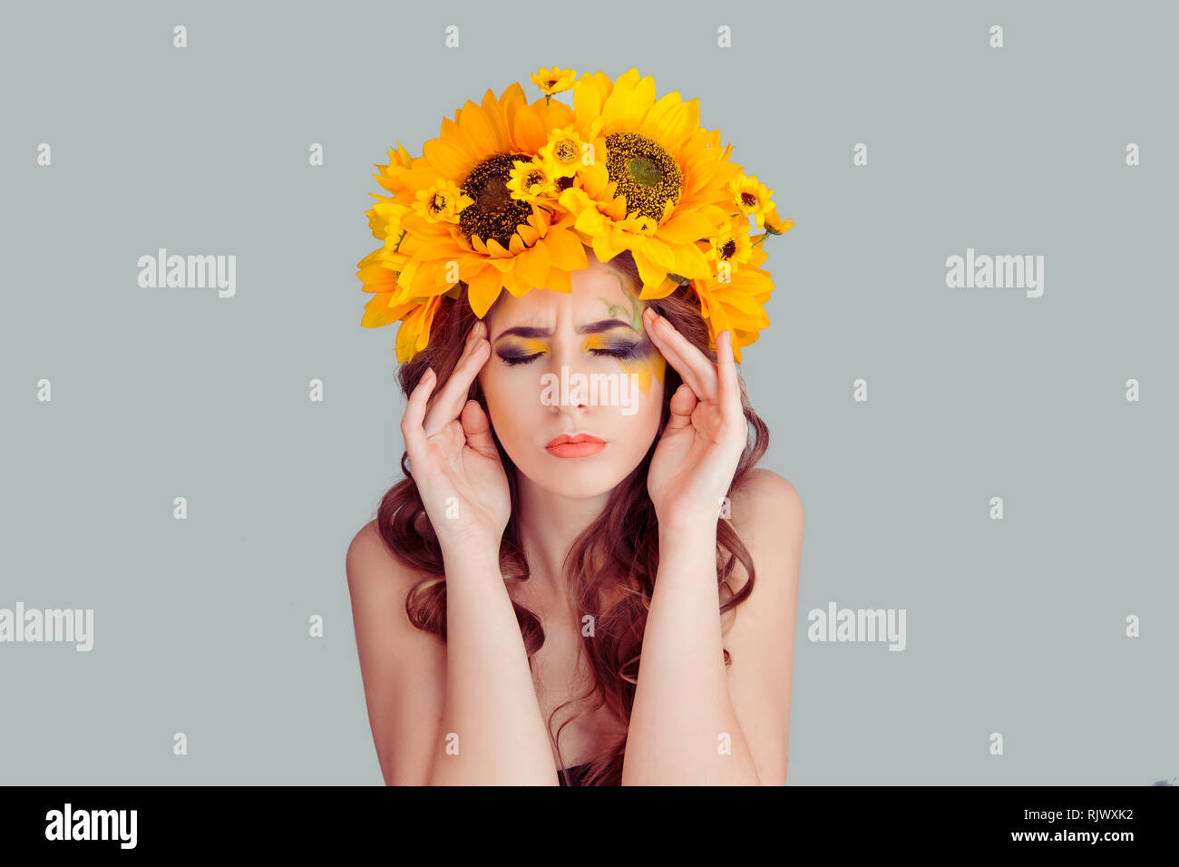 Woman with floral headband touching temples thinking hard Stock Photo ...