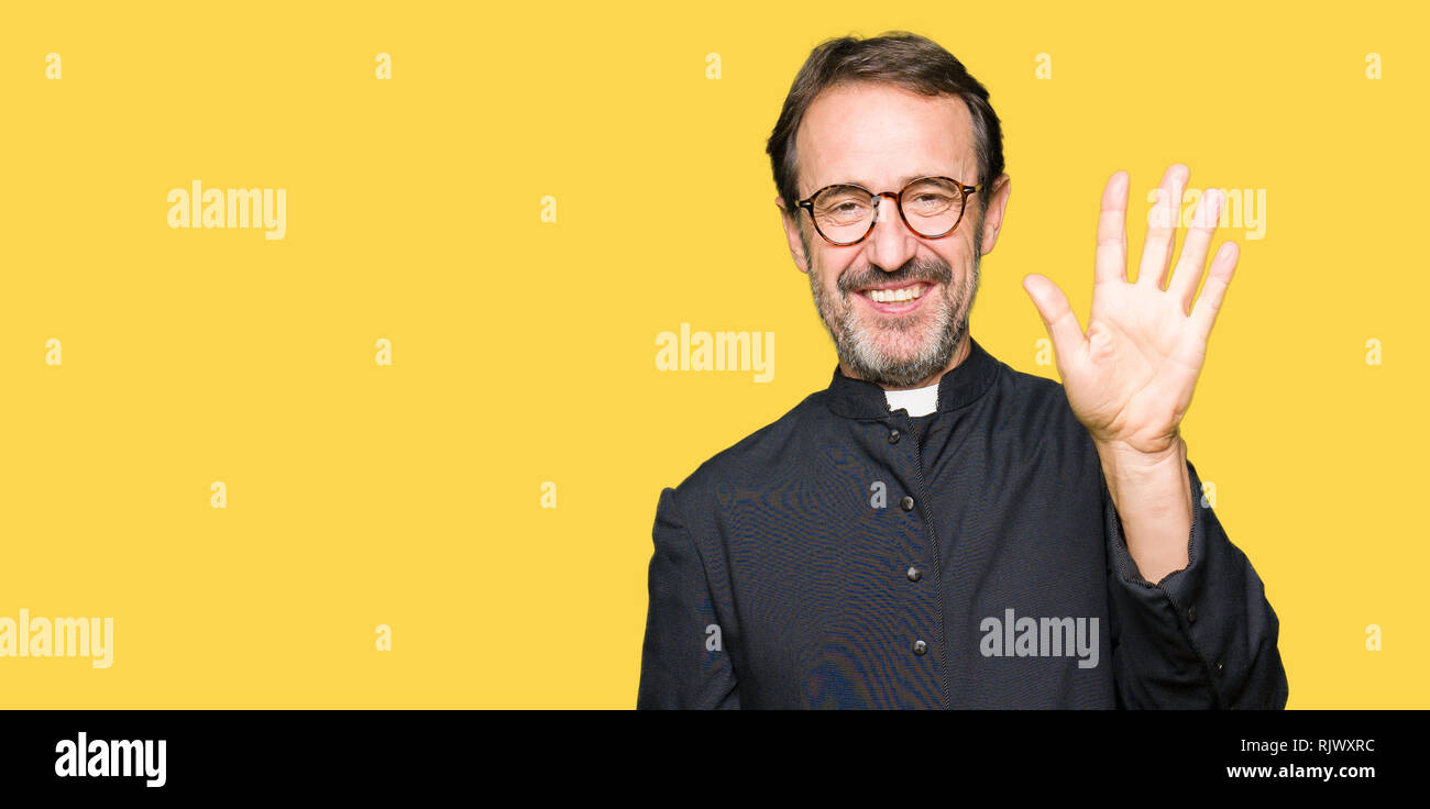 Middle age priest man wearing catholic robe showing and pointing up ...