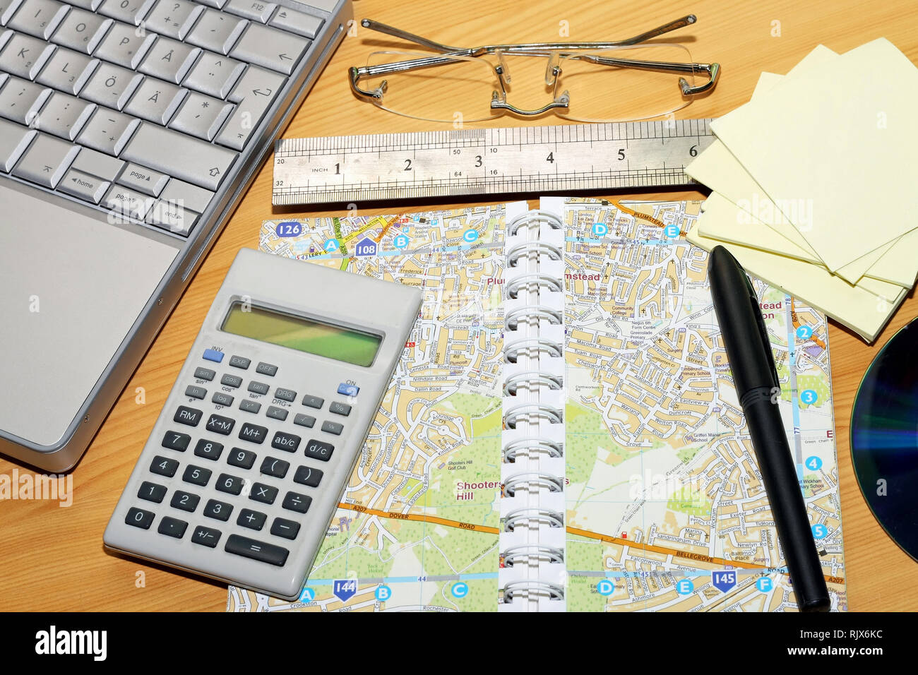 Notebook map and calculator at wooden desk Stock Photo - Alamy