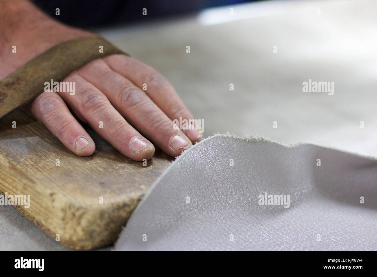 horizontal closeup of a white man smoothing a sheet of blue leather ...