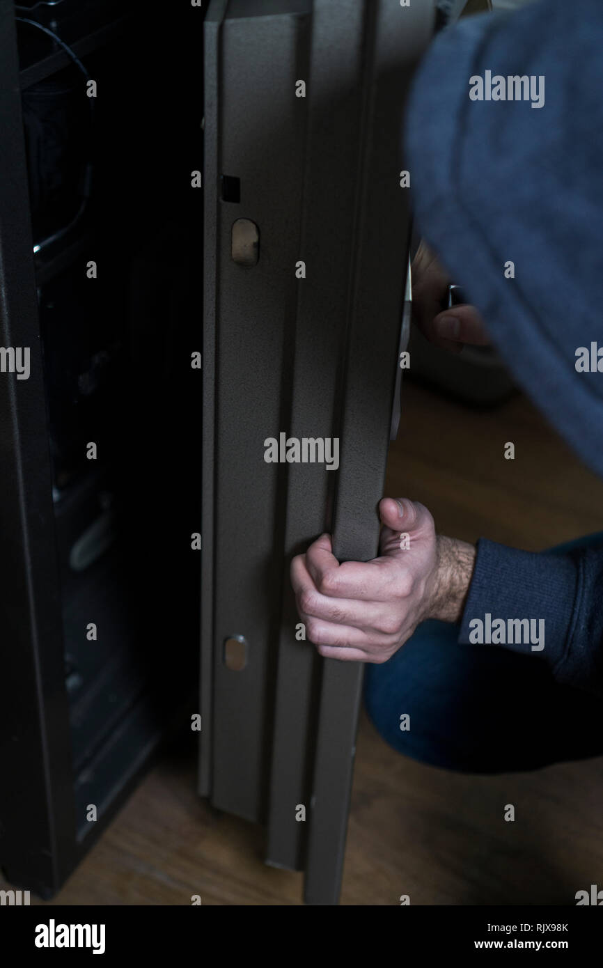 Hooded criminal thief stealing a safe Stock Photo - Alamy
