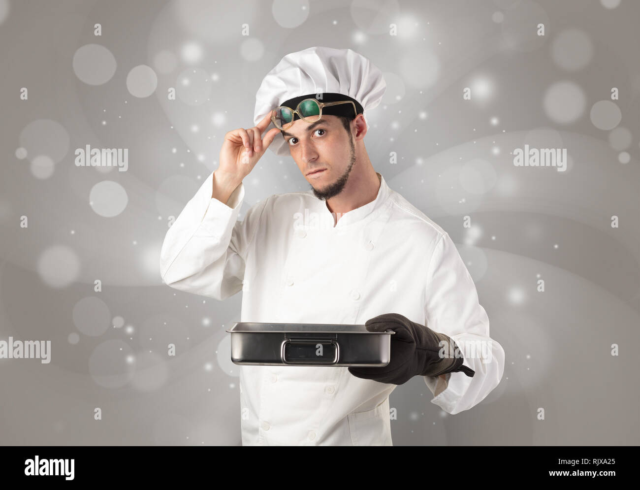 Male cook with kitchen tools and shiny grey wallpaper Stock Photo - Alamy