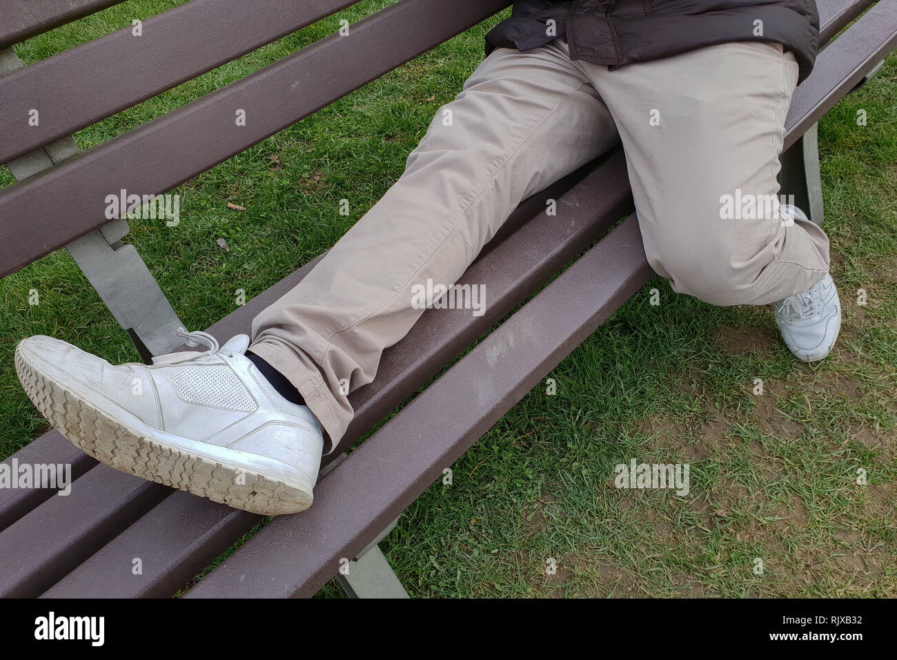 The legs of a man sitting on a bench in the park Stock Photo - Alamy