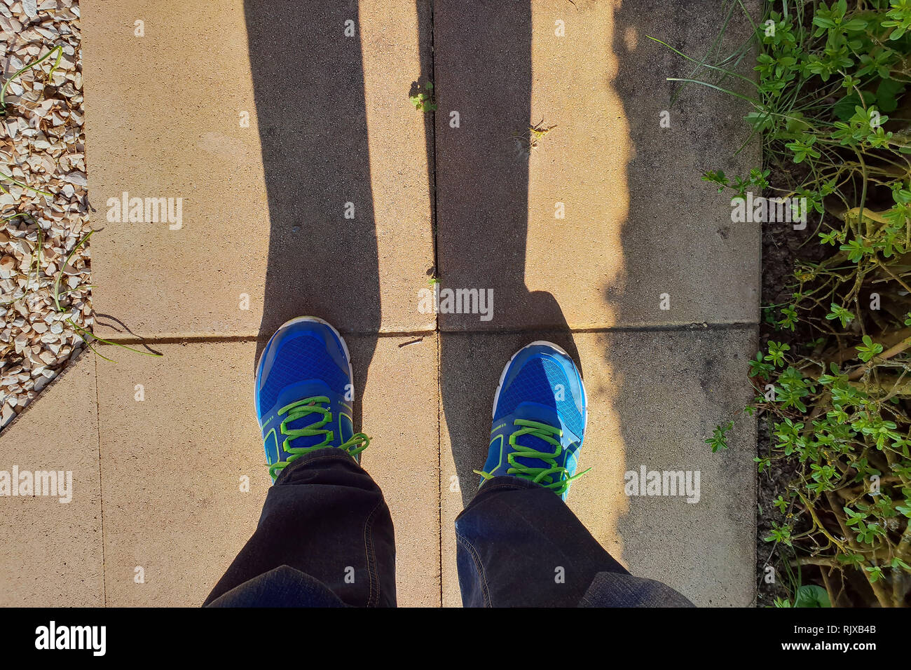 Shadows from feet in blue shoes Stock Photo - Alamy