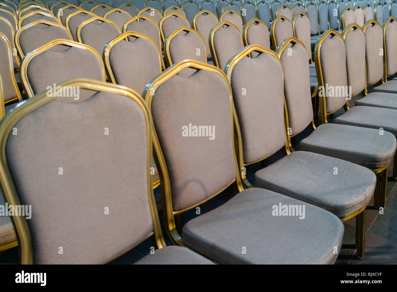 Rows of traditional hard wood chairs with soft cushion and golden ...