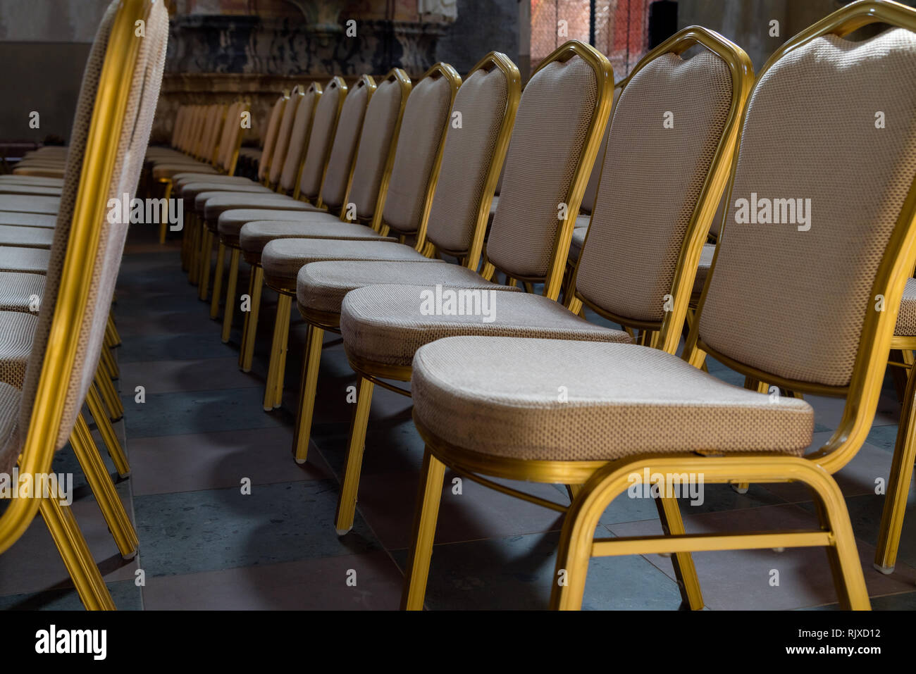 Rows of traditional hard wood chairs with soft cushion and golden ...
