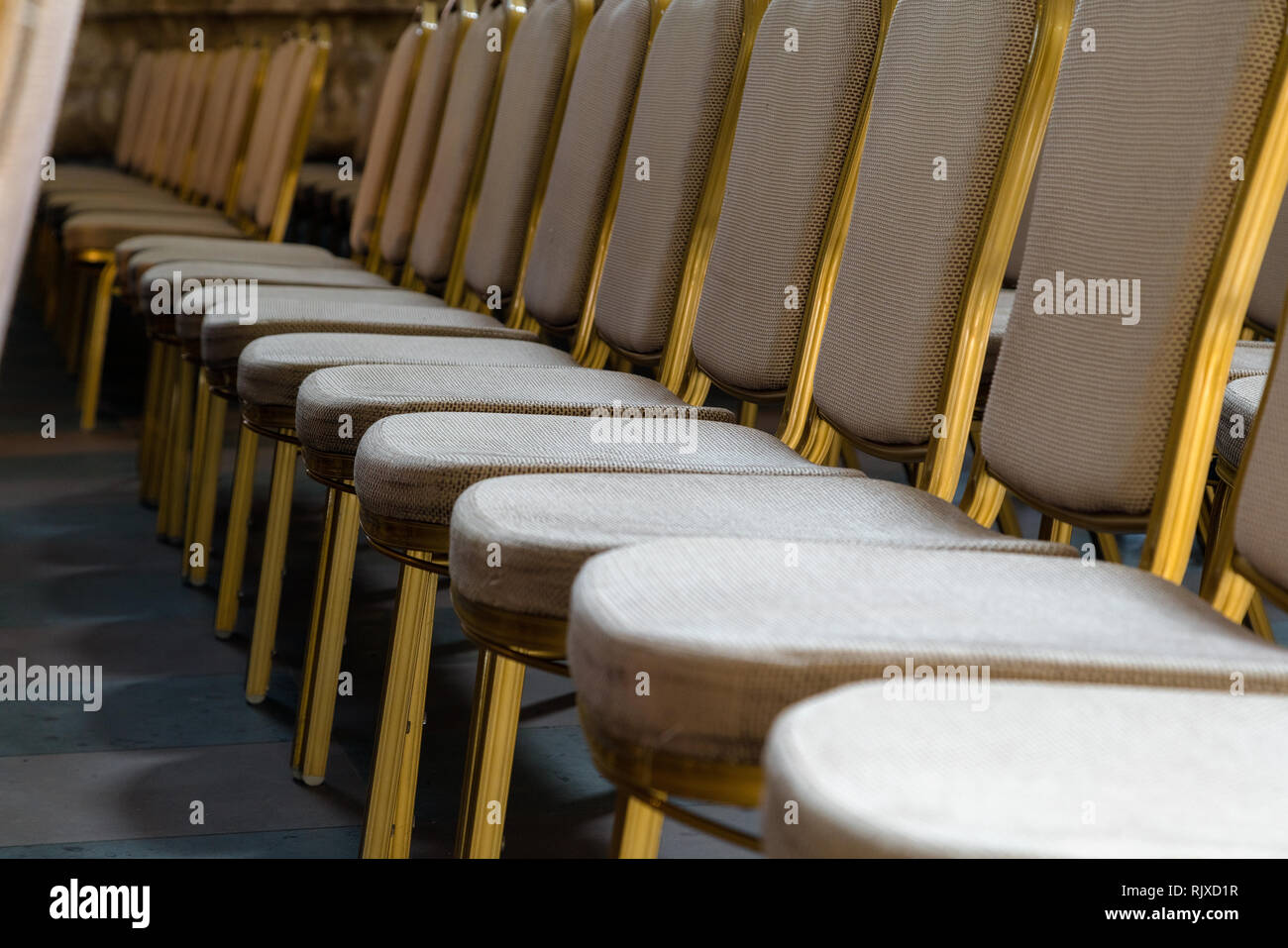 Rows of traditional hard wood chairs with soft cushion and golden ...