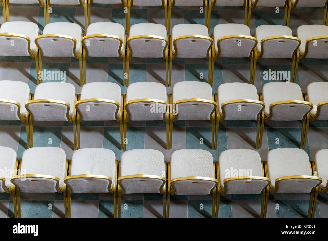 Rows of traditional hard wood chairs with soft cushion and golden ...