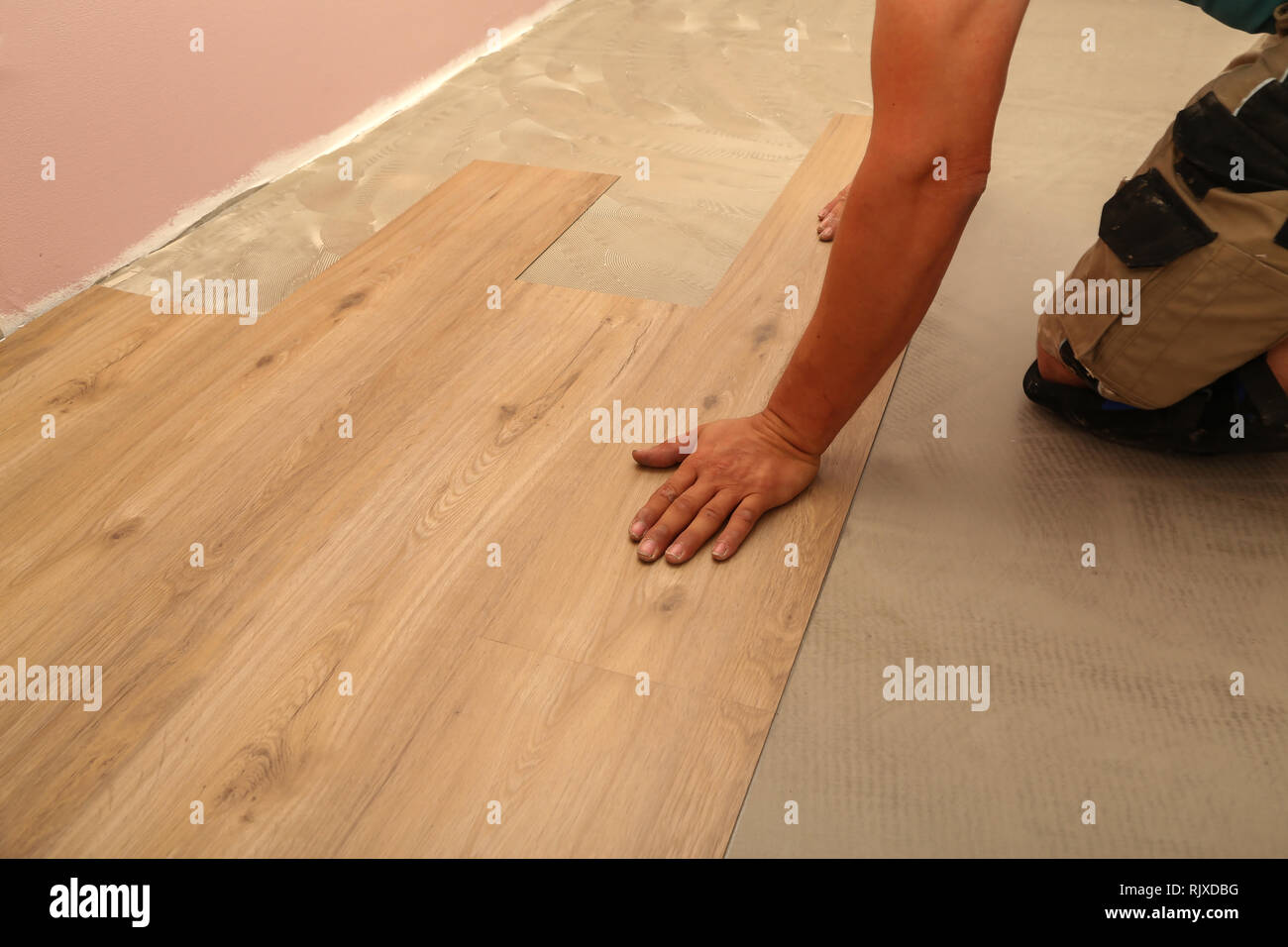 Work on laying flooring. Worker installing new vinyl tile floor Stock ...