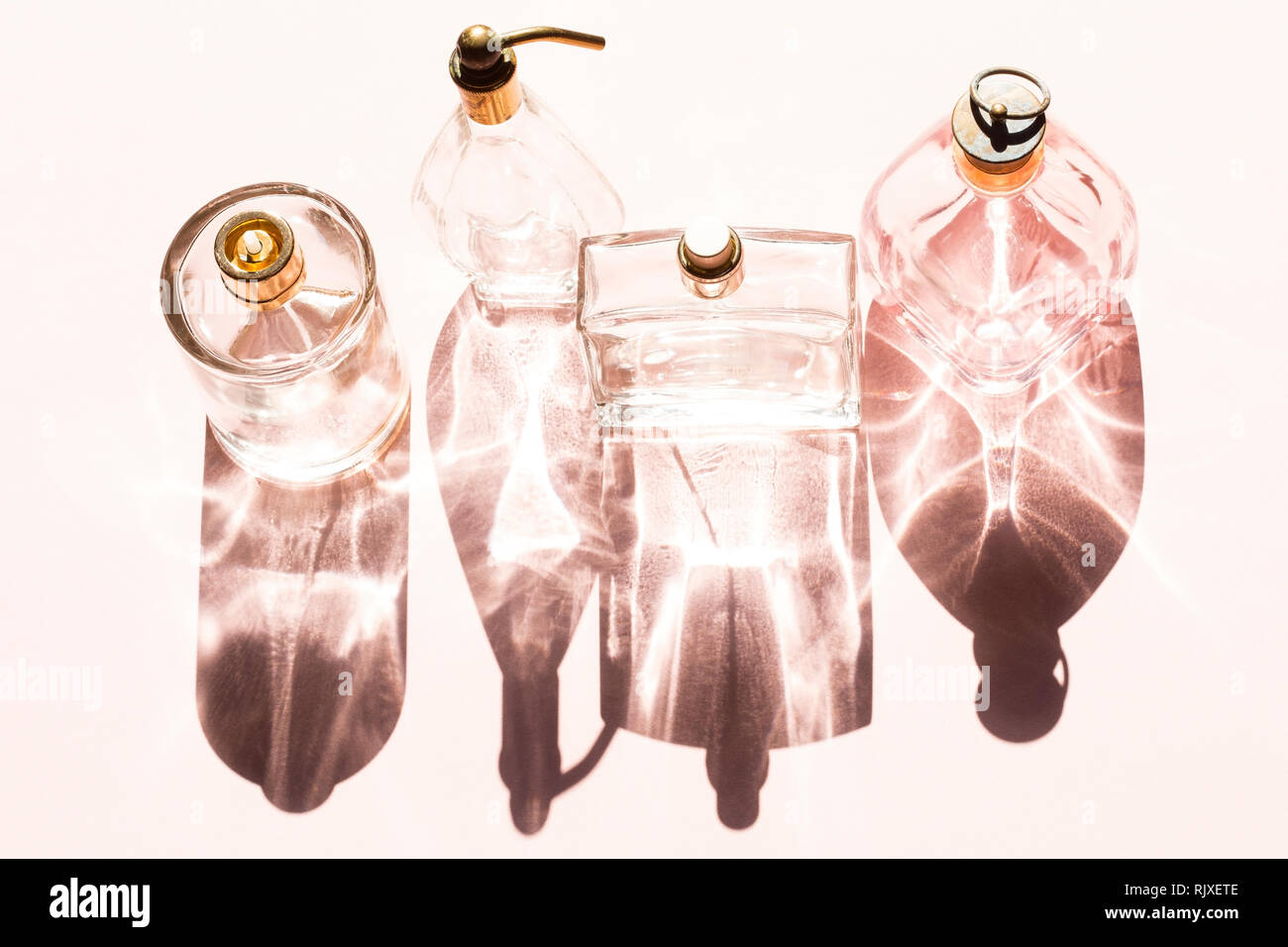 Perfume bottles on a bright light with the shadows Stock Photo - Alamy