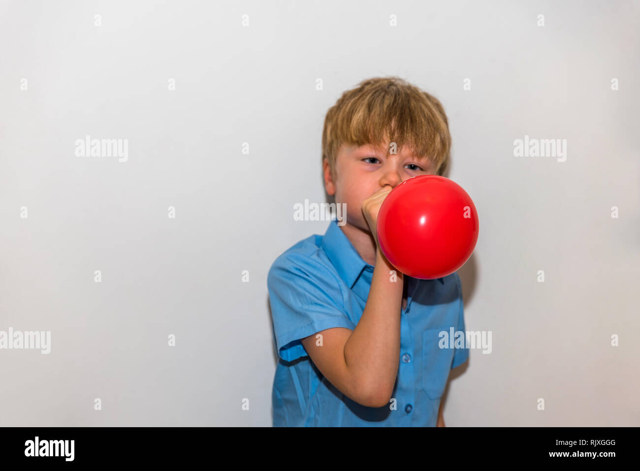 Boy blowing up red balloon hi-res stock photography and images - Alamy