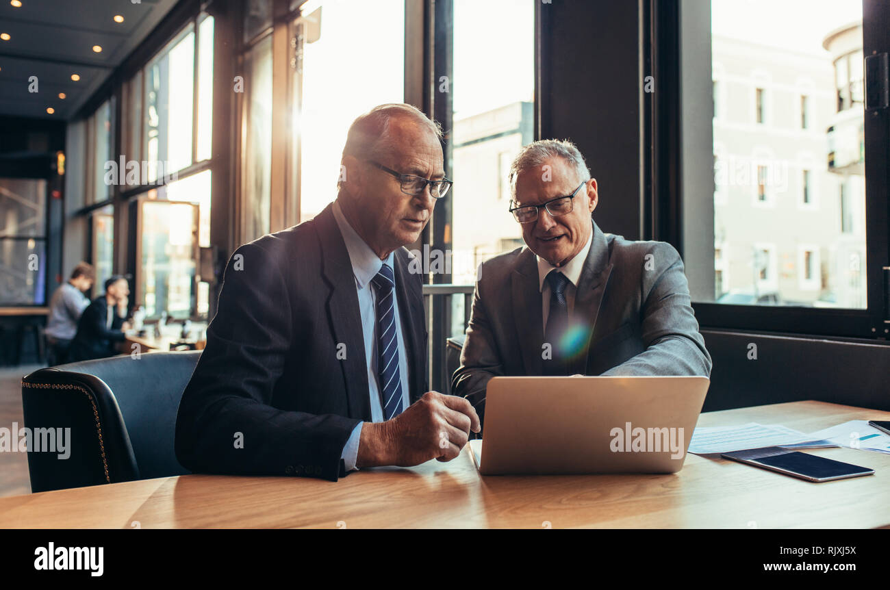 Two senior business partners discussing some project at the cafe ...