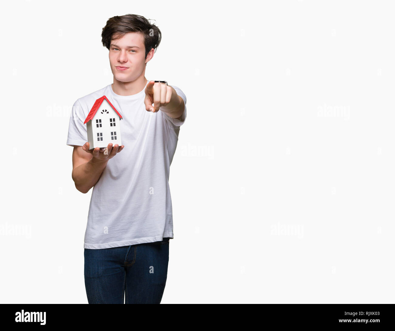 Young man holding house over isolated background pointing with finger ...