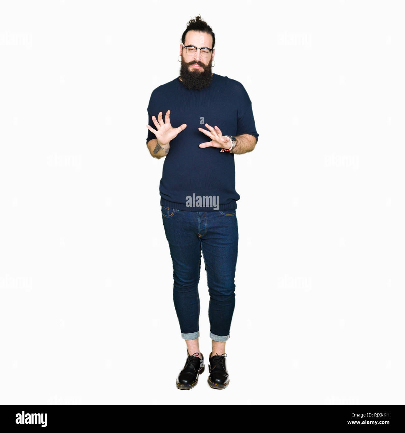 Young hipster man with long hair and beard wearing glasses disgusted ...