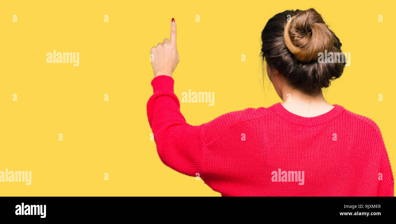 Young beautiful woman wearing red sweater and bun Posing backwards ...