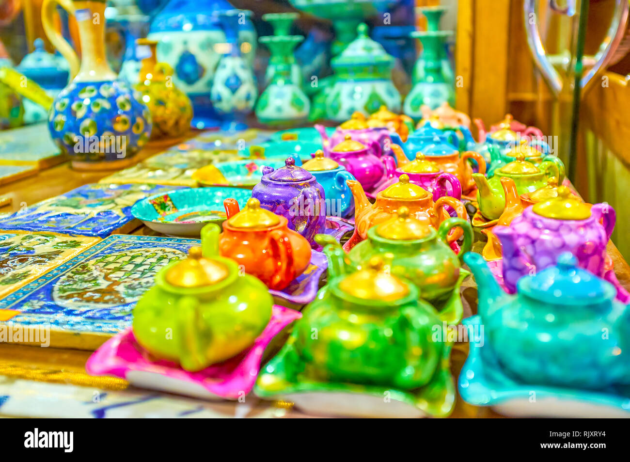 The colorful kettles, plates and painted tiles in a pottery stall in ...