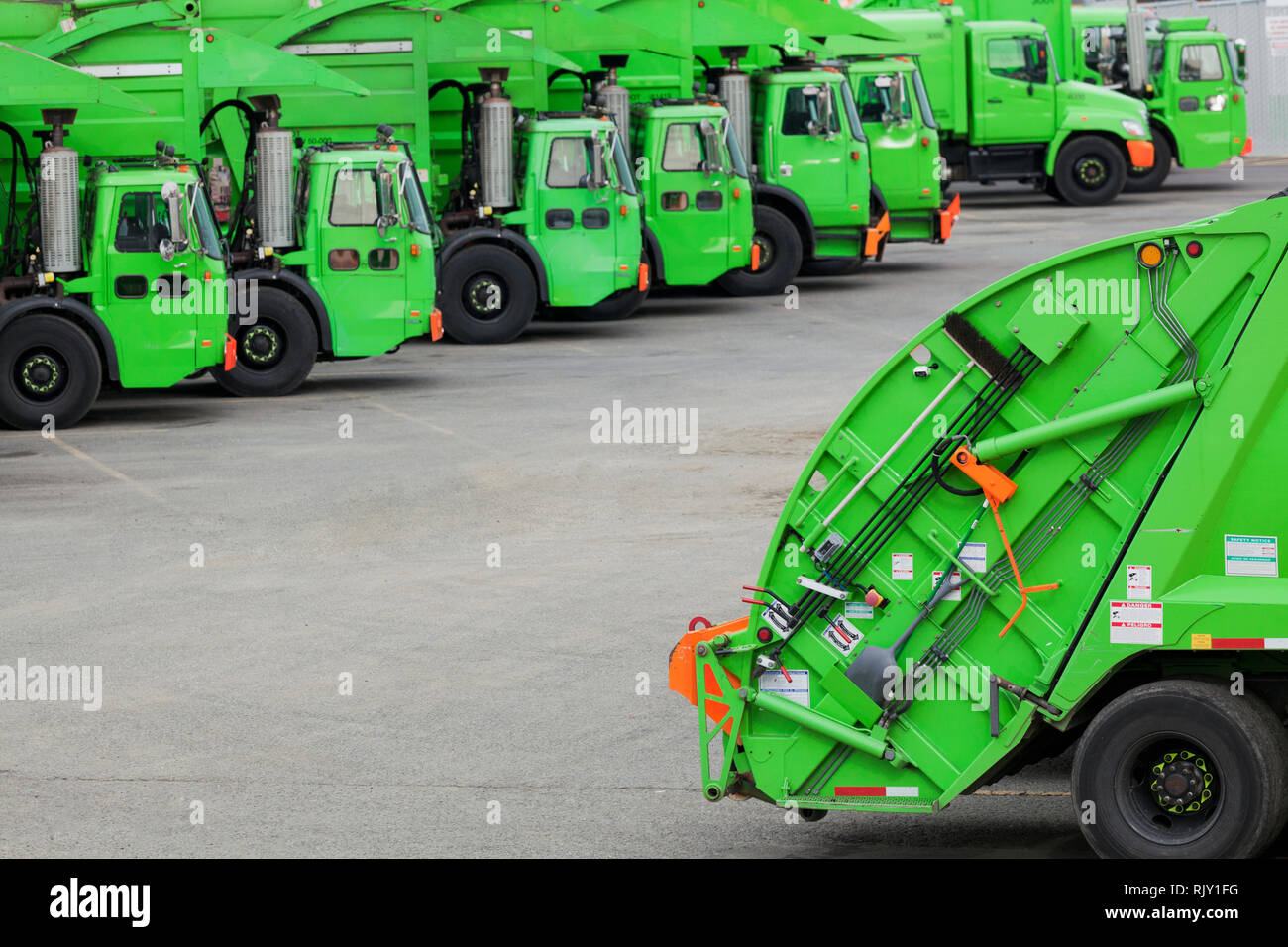 Green garbage trucks in parking lot Stock Photo - Alamy