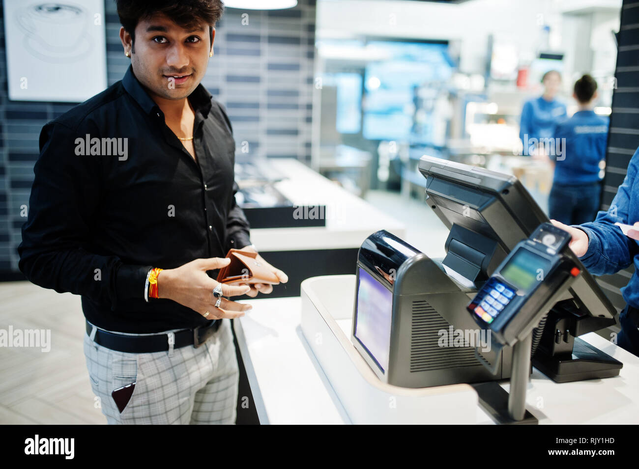 Indian man holding wallet behind his pay cash desk with order screen ...