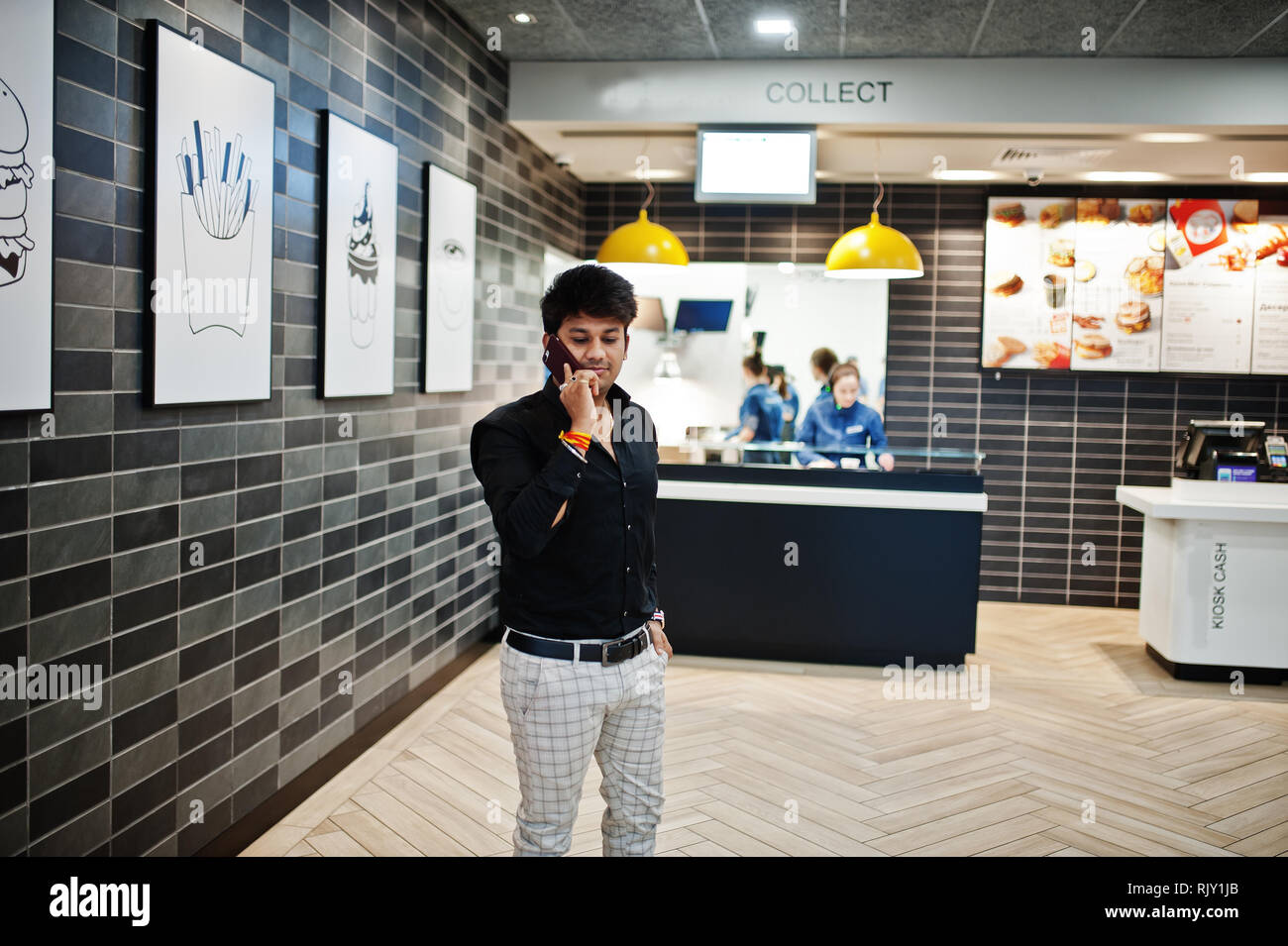 Indian man speaking on mobile phone while waiting for his order in the ...